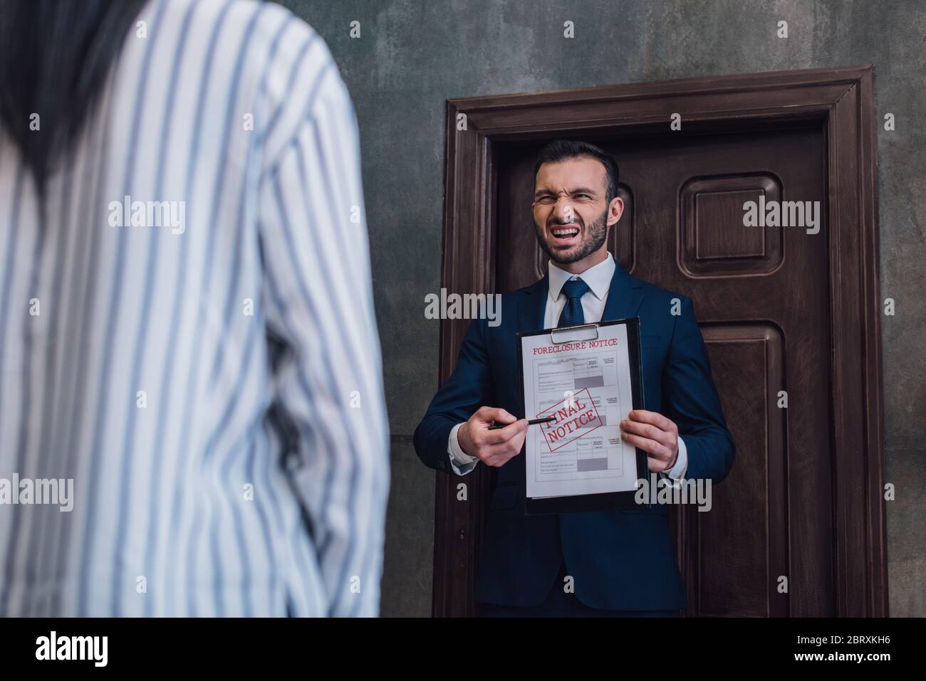 Angry collector pointing with pen at documents with foreclosure and ...
