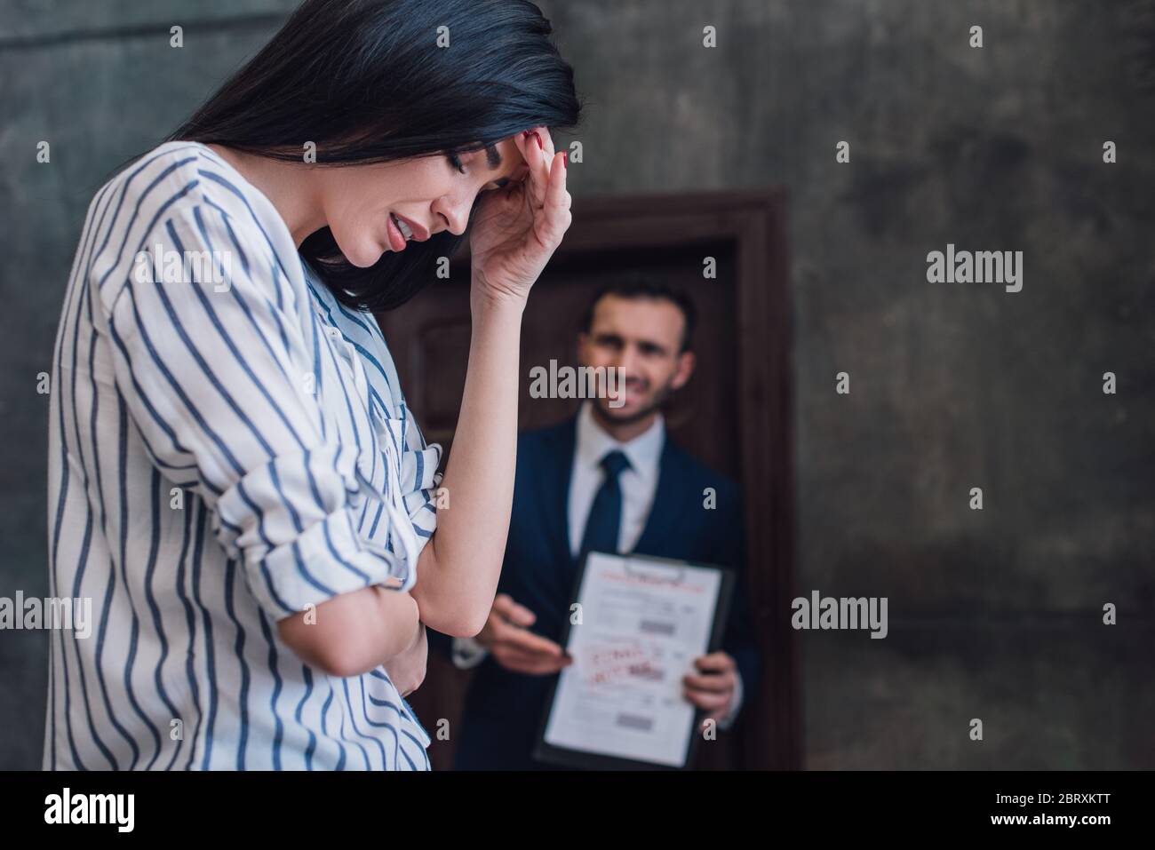 Selective focus of upset woman and angry collector with documents in ...