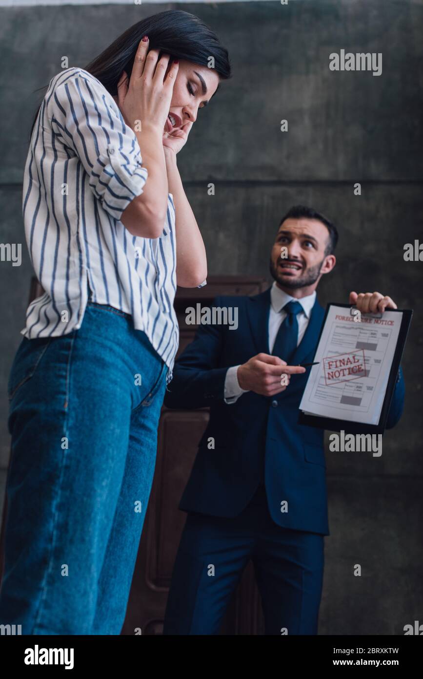 Low angle view of angry collector pointing at documents with ...