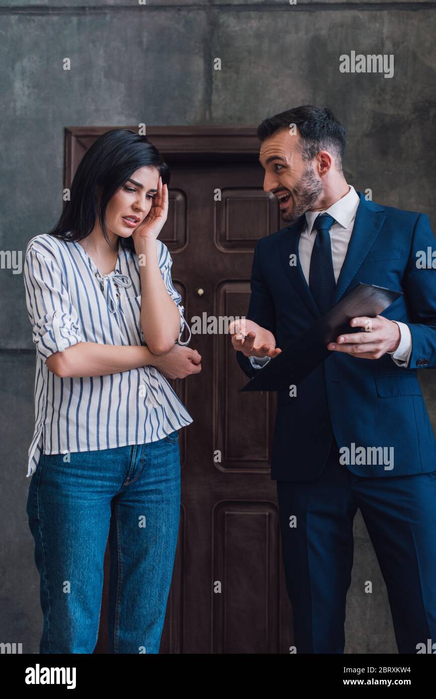 Angry collector pointing at documents near stressed woman in room Stock ...