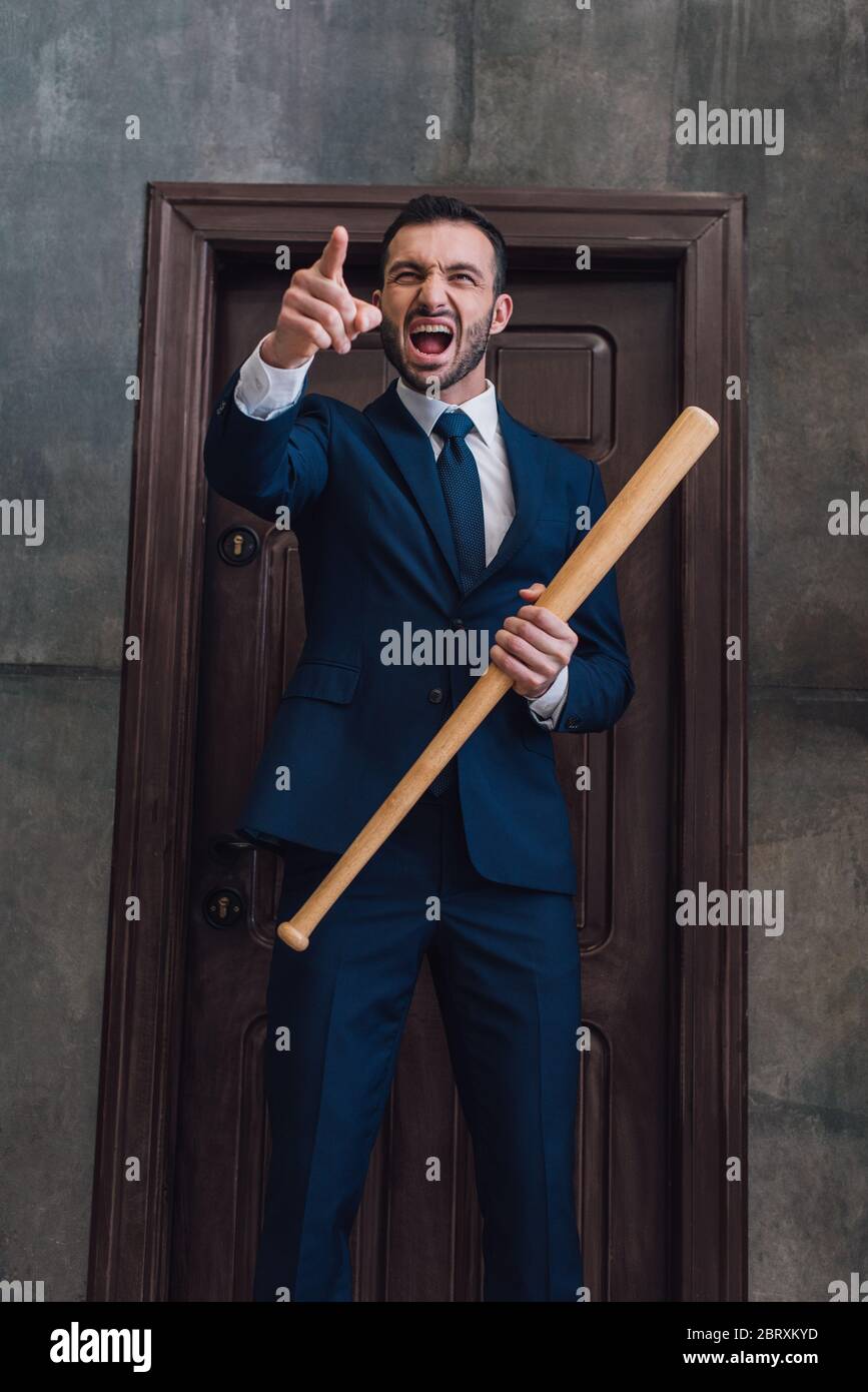 Angry collector with baseball bat pointing with finger and shouting ...