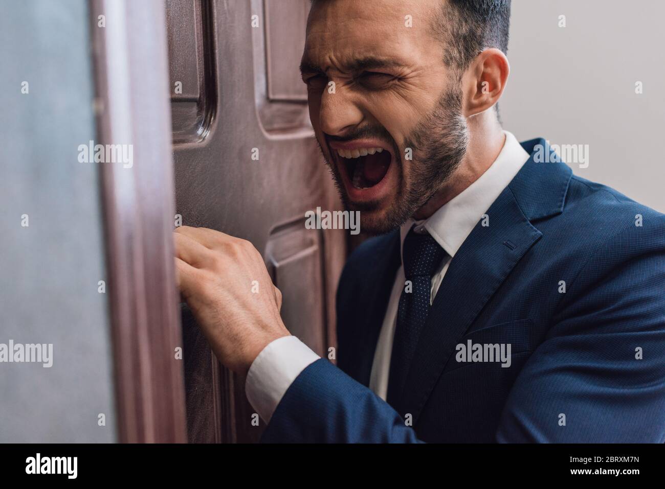 Selective focus of angry collector shouting and knocking on door Stock ...