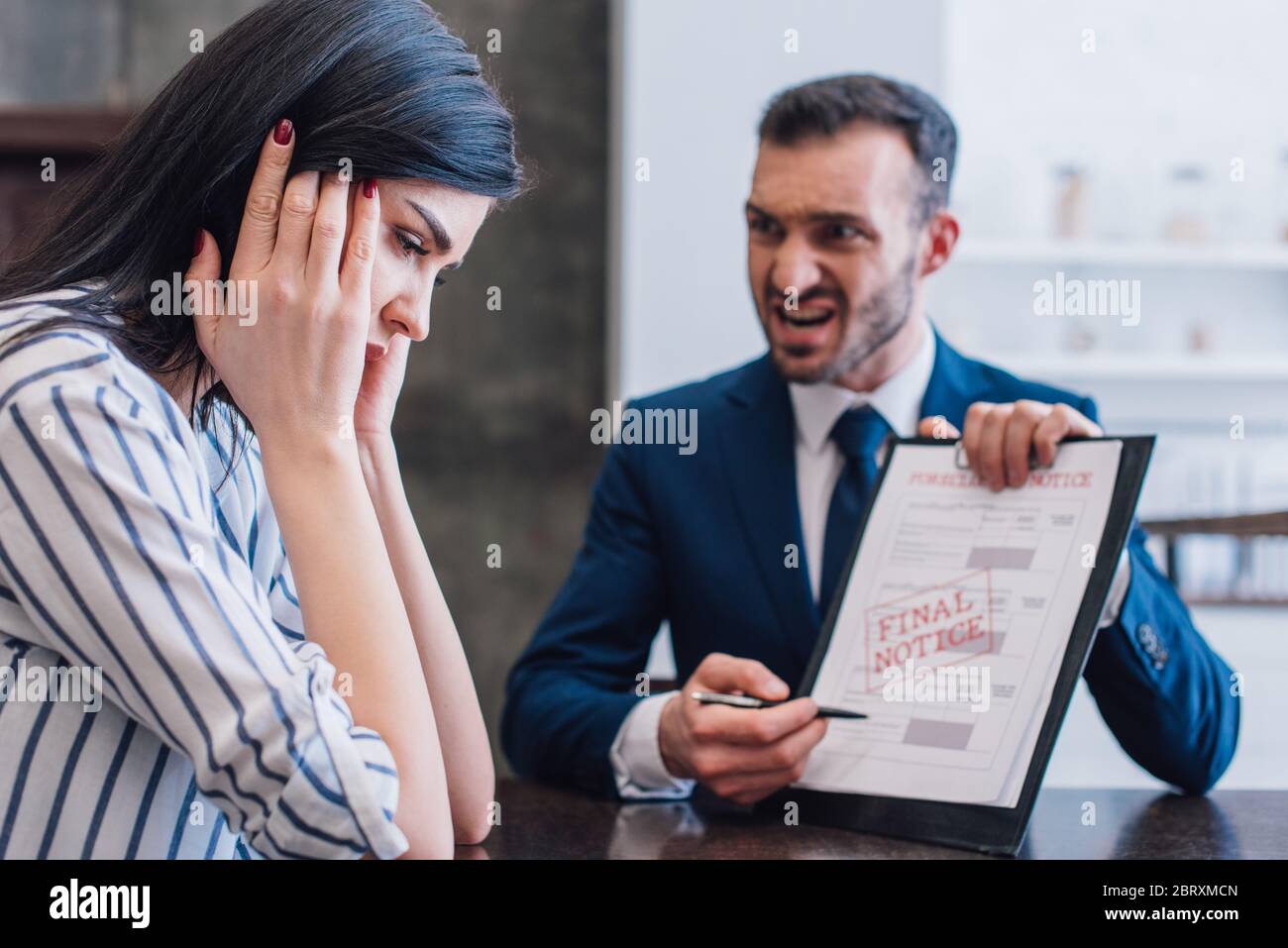 Selective focus of stressed woman and angry collector pointing with pen ...