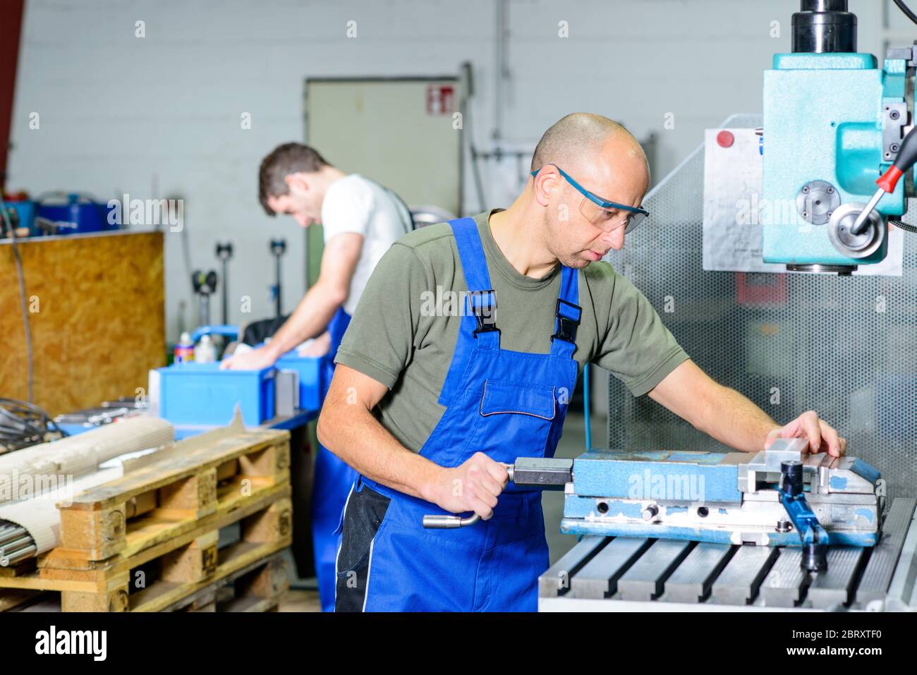 two worker in factory on work bench and machine Stock Photo - Alamy