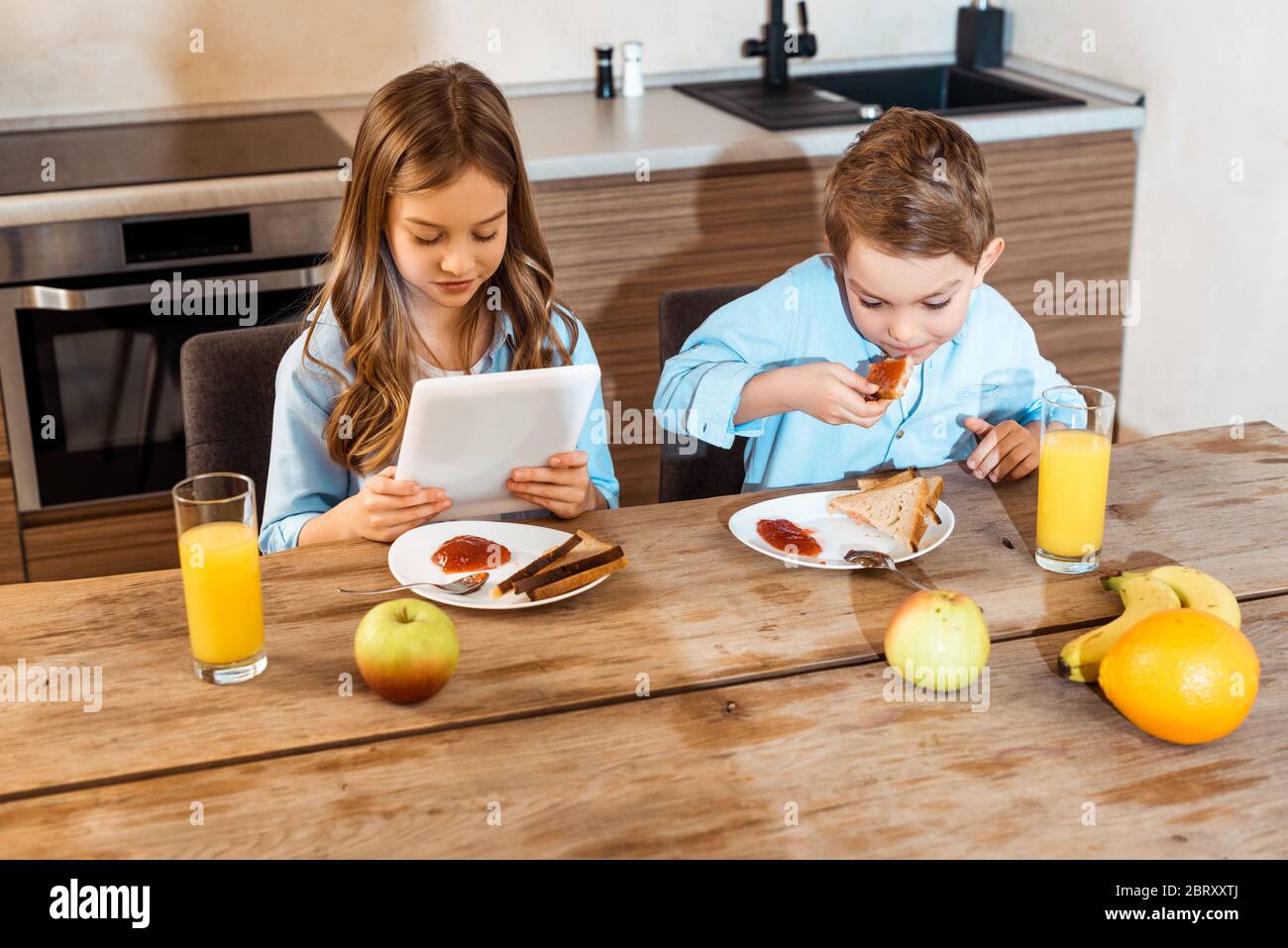 boy eating toast bread with jam near sister using digital tablet Stock ...