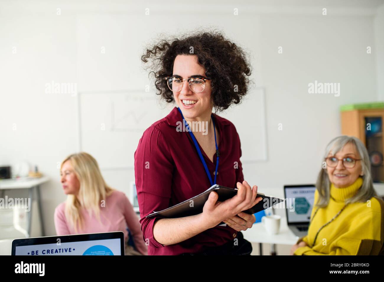 Portrait of teacher with seniors attending computer and technology ...