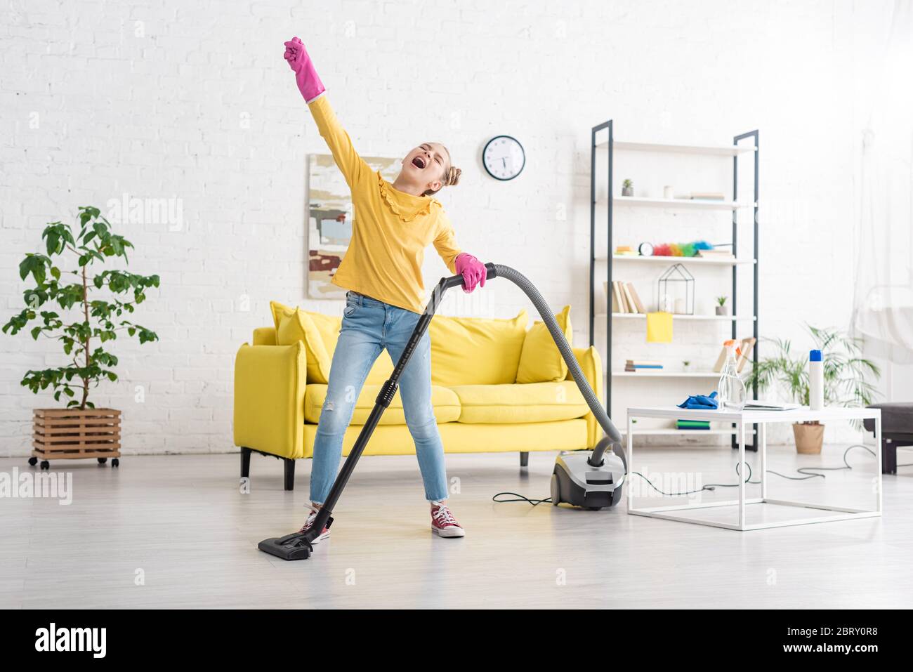 Child with closed eyes and outstretched hand singing with vacuum ...
