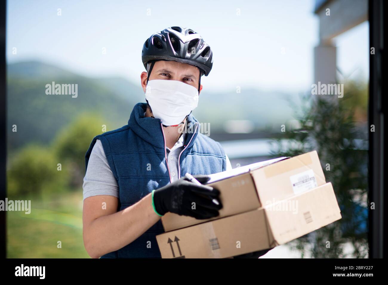 Courier with face mask delivering parcel, corona virus and quarantine ...