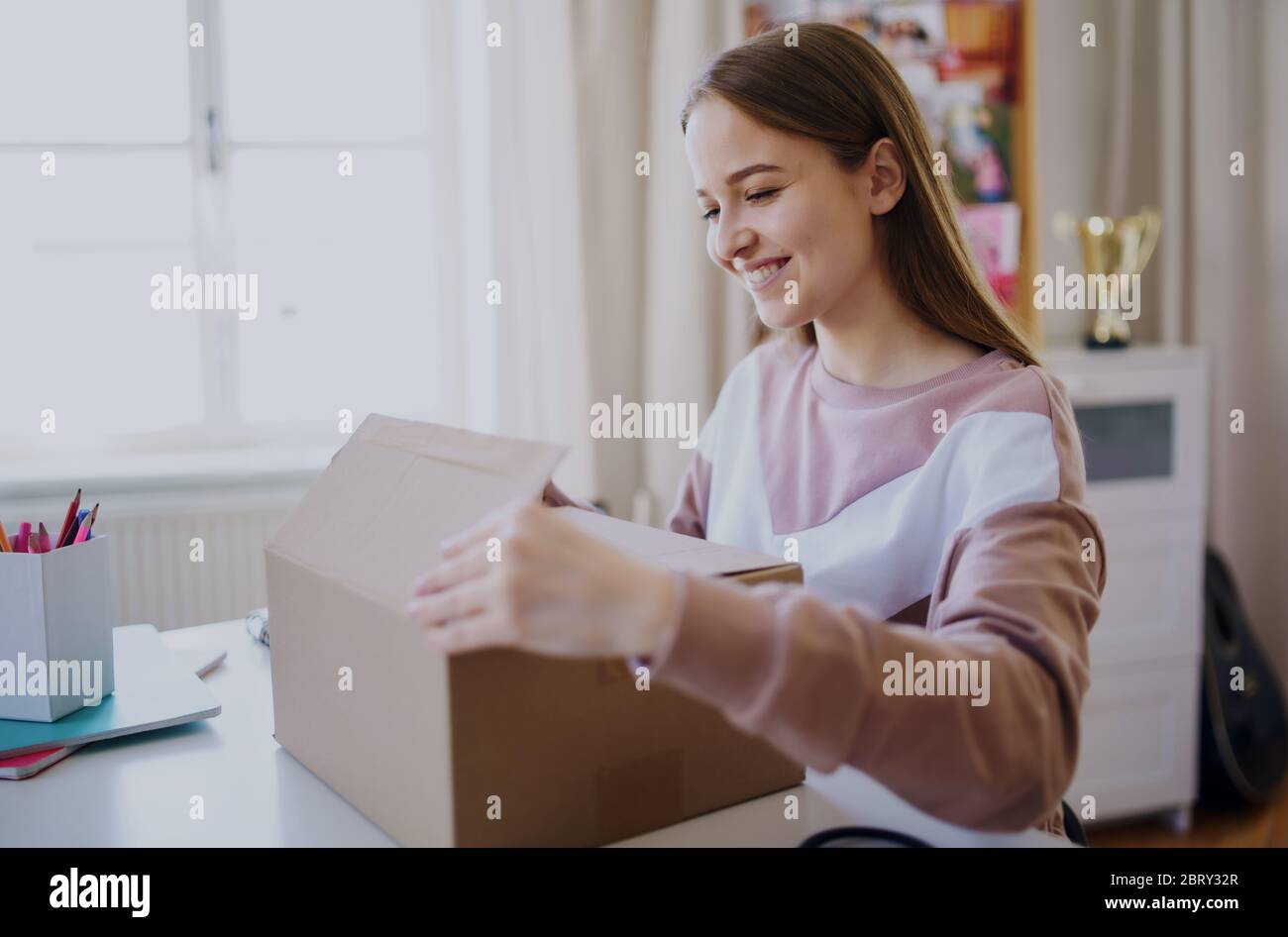 Young female student at the table, opening parcel box Stock Photo - Alamy