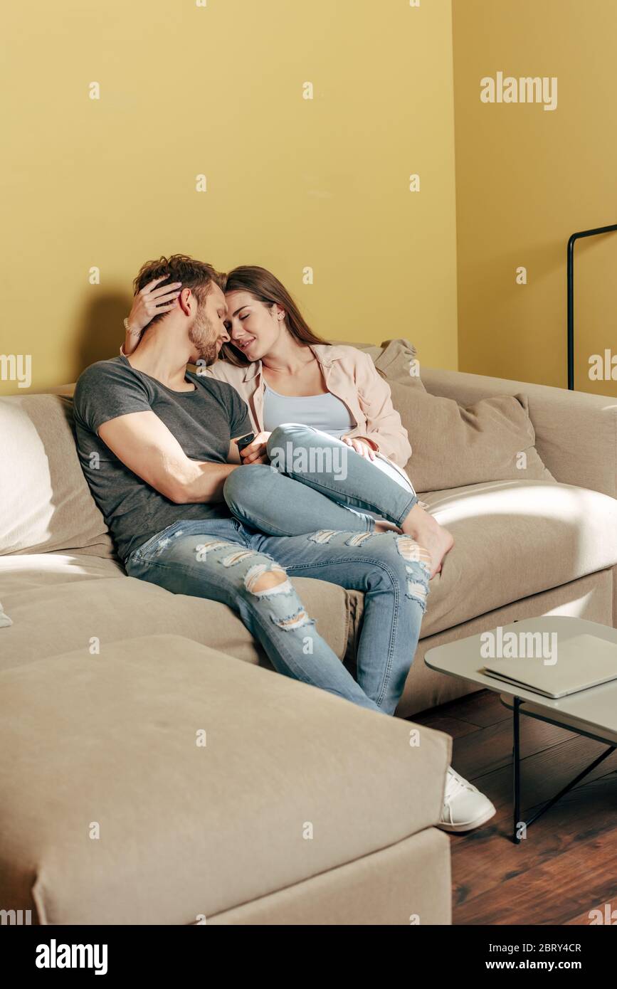 couple hugging and sitting on sofa in living room Stock Photo - Alamy