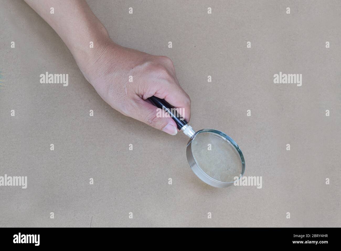 Hand holding a magnifying glass with brown paper background Stock Photo ...