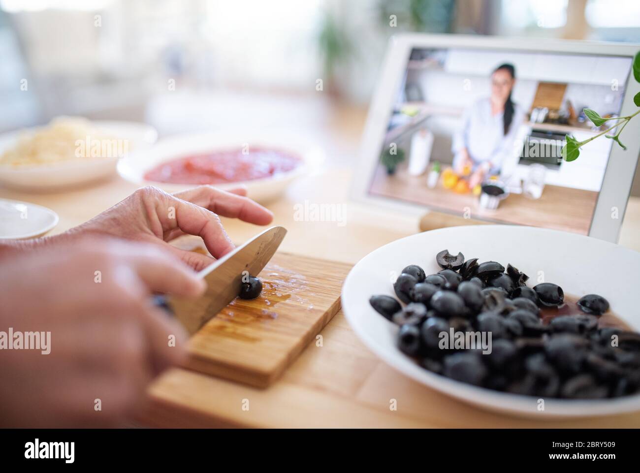 Senior woman preparing food in kitchen indoors, following food vlogger ...