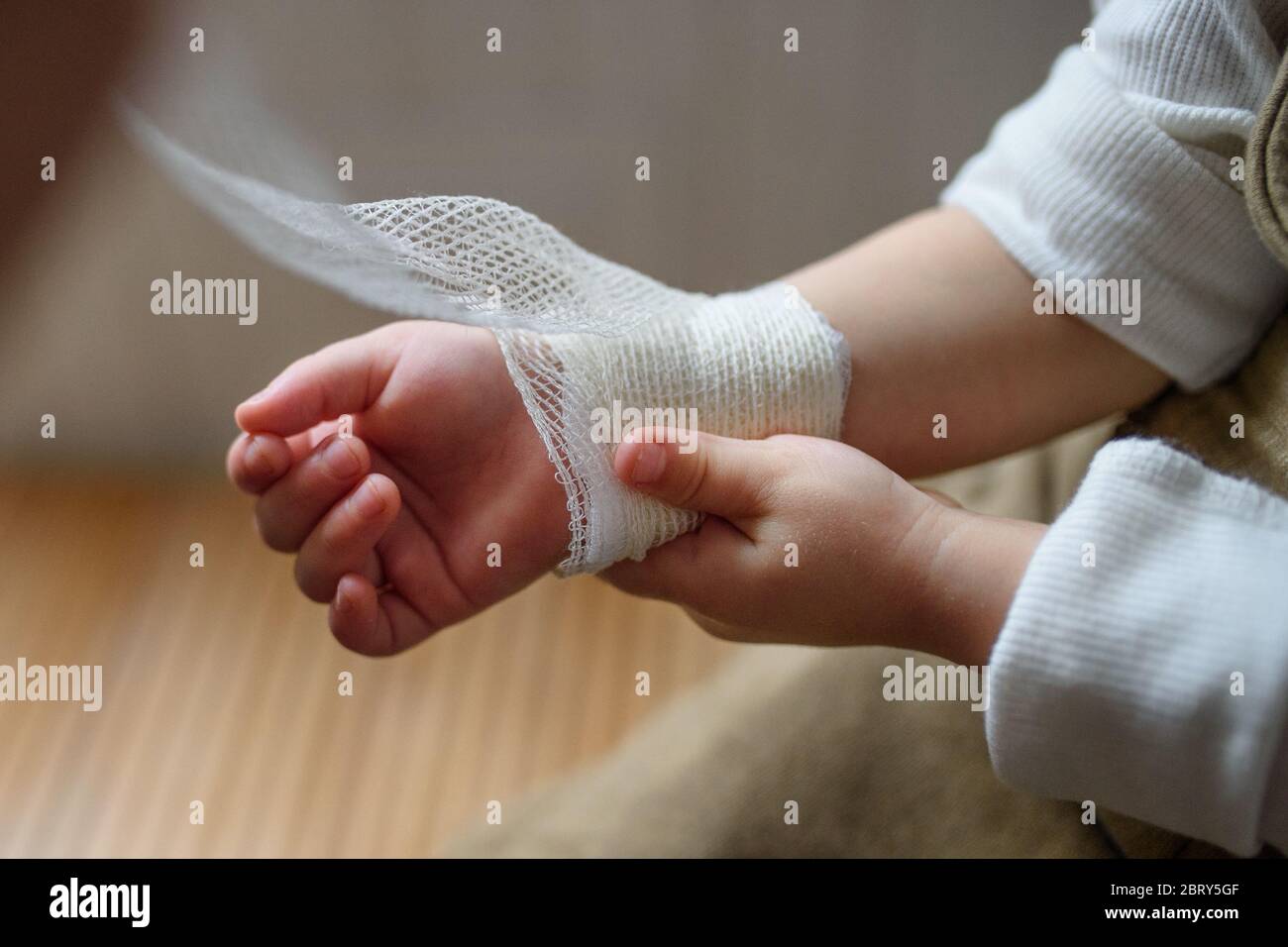 Hands of unrecognizable hurt small child with bandage indoors at home ...