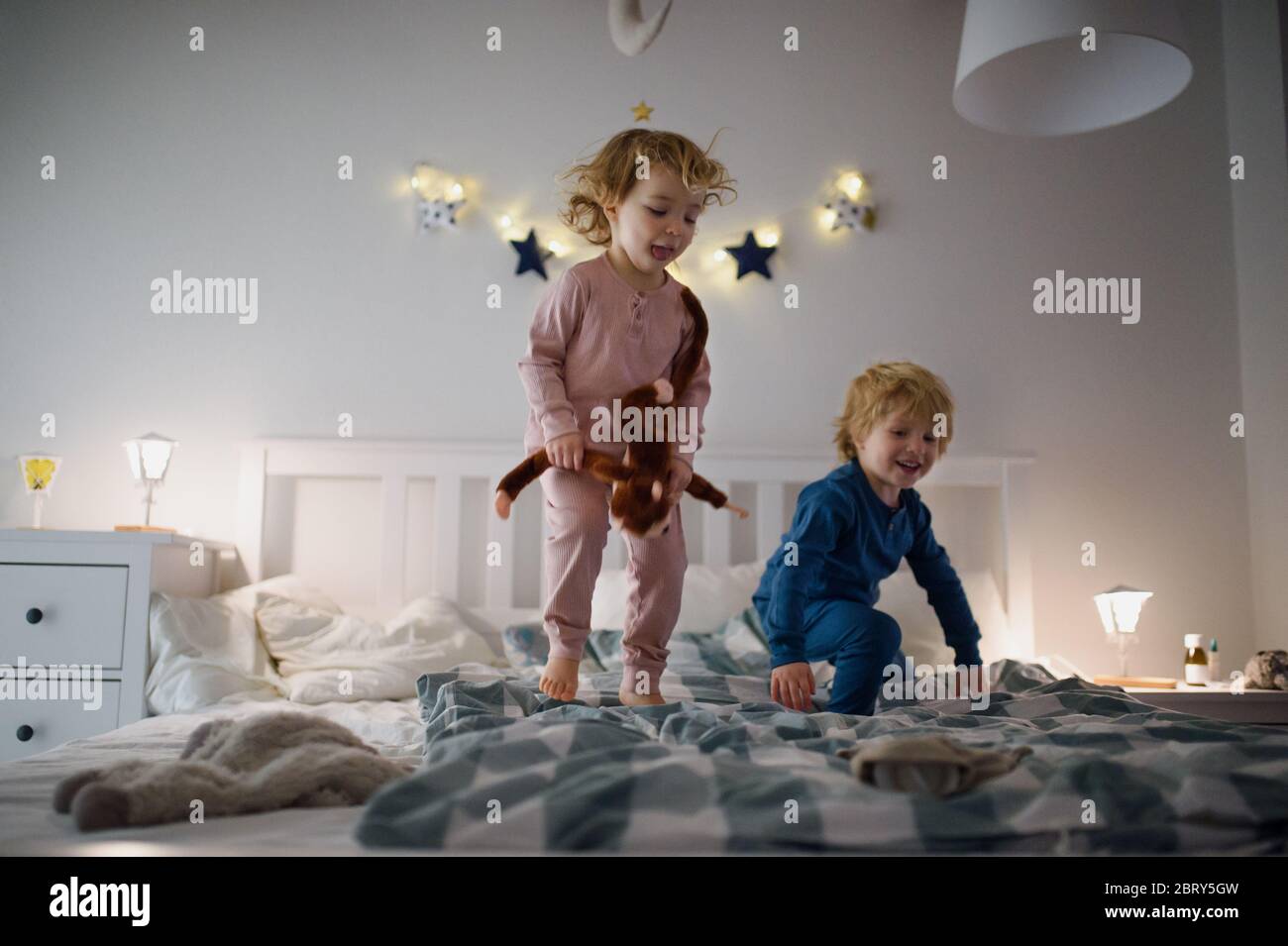 Two small children jumping on bed indoors at home, having fun Stock ...