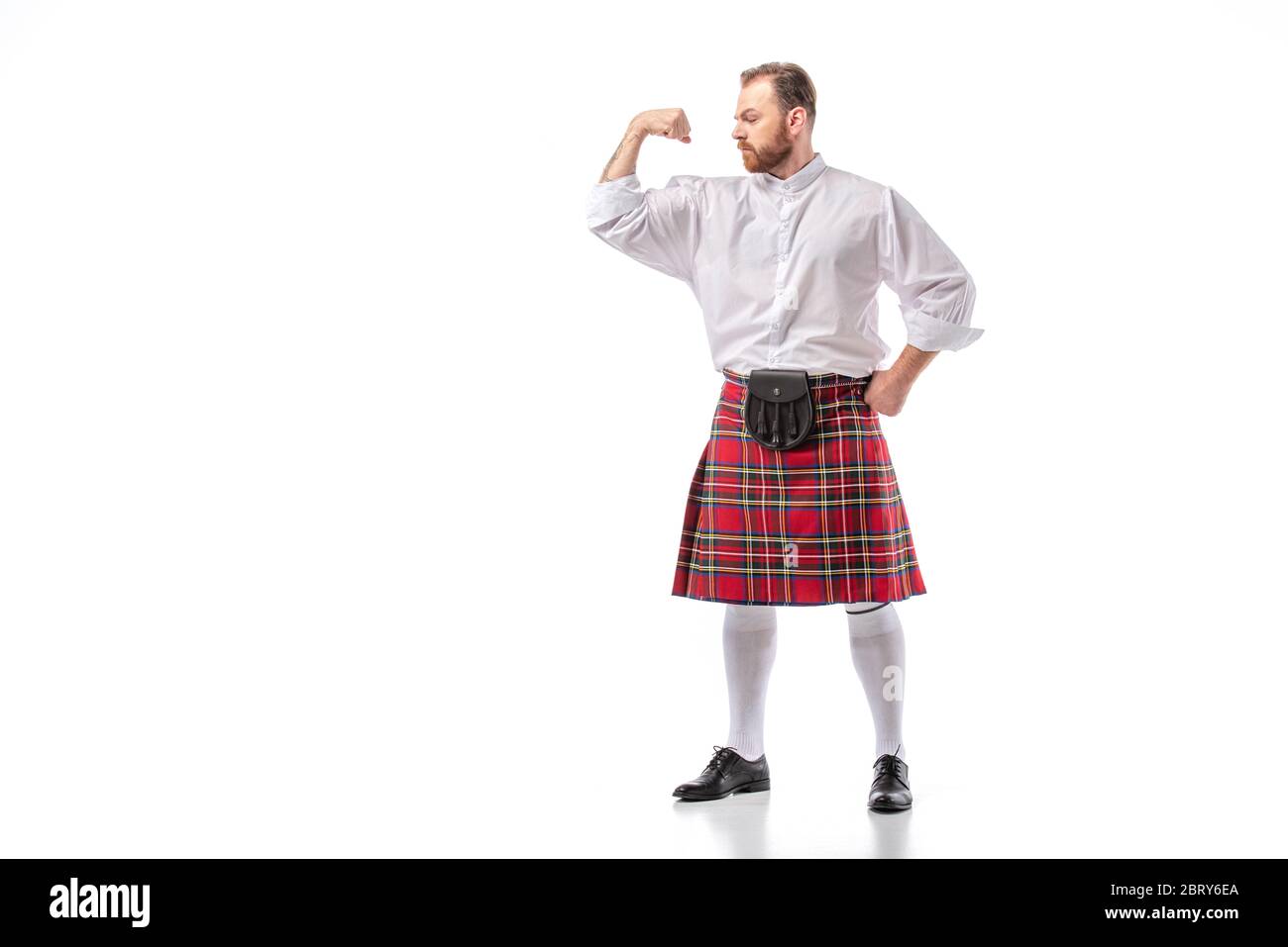 strong Scottish redhead bearded man in red tartan kilt showing biceps ...