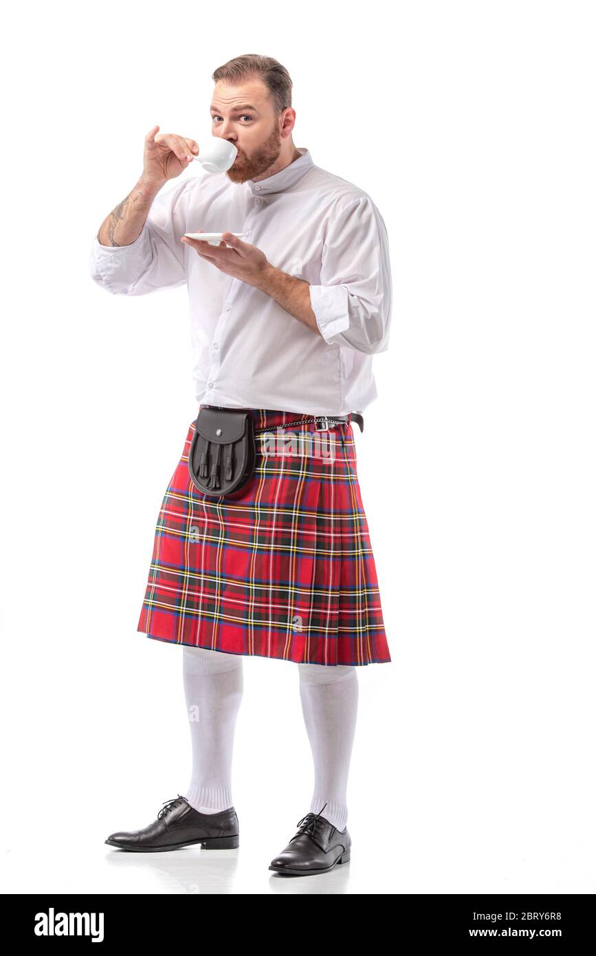 Scottish redhead man in red kilt drinking coffee on white background ...