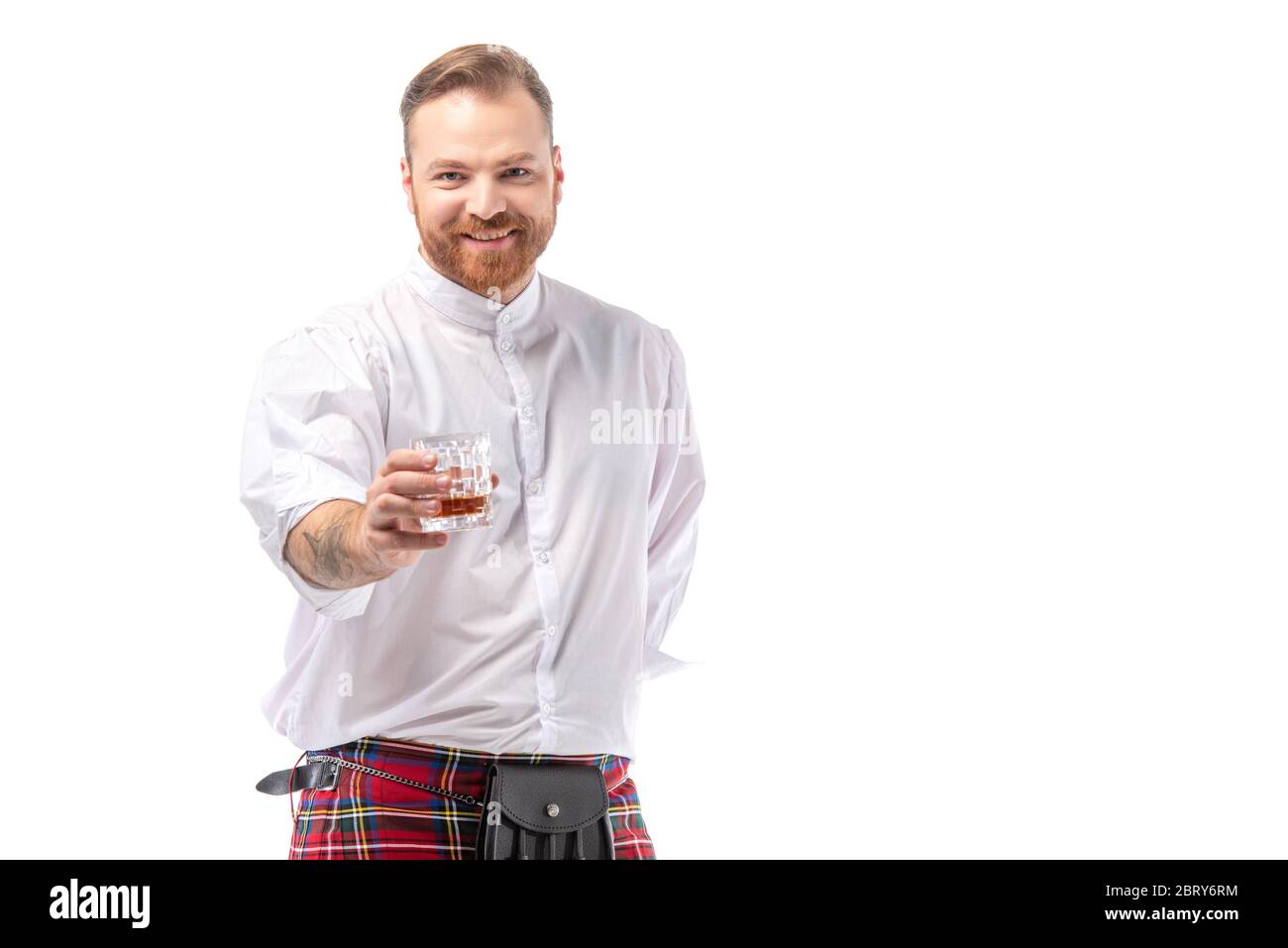 smiling Scottish redhead man in red kilt with whiskey in glass isolated ...