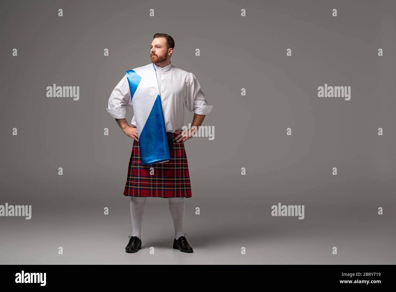 serious Scottish redhead man in red kilt with flag of Scotland and ...