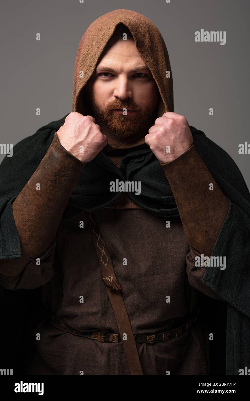 serious medieval Scottish redhead man in mantel showing fists on grey ...