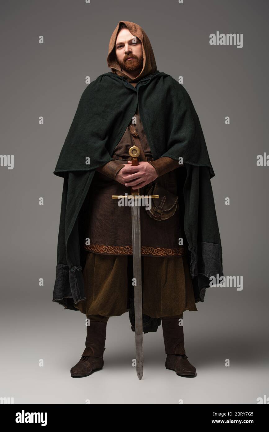 medieval Scottish redhead knight in mantel with sword on grey ...