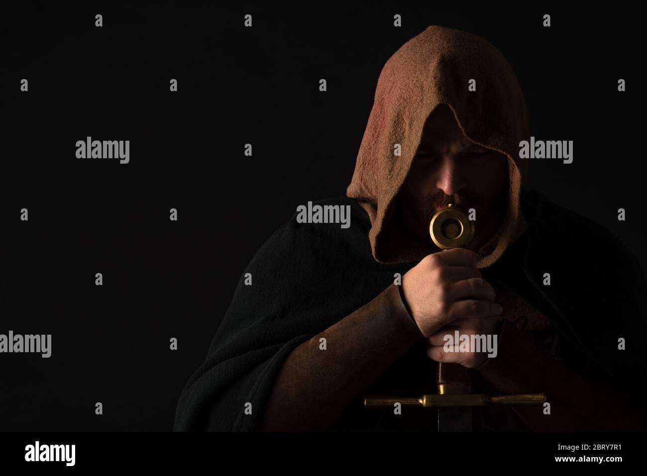 medieval Scottish man in mantel with sword in dark isolated on black ...