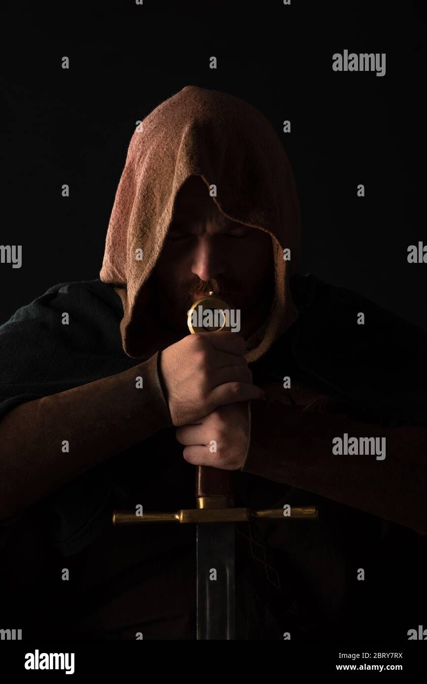 medieval Scottish man in mantel with sword in dark isolated on black ...