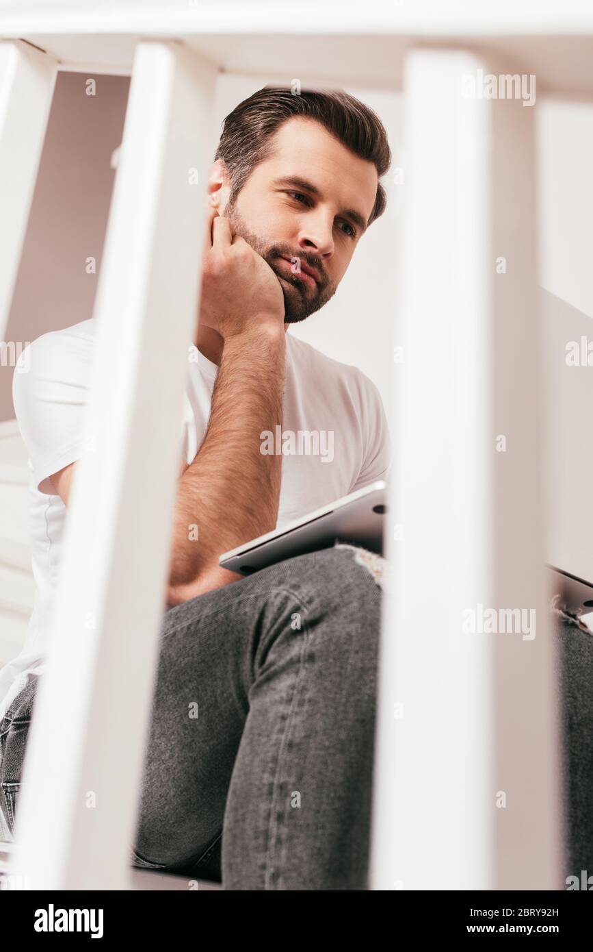 Selective focus of teleworker using laptop on staircase at home Stock ...