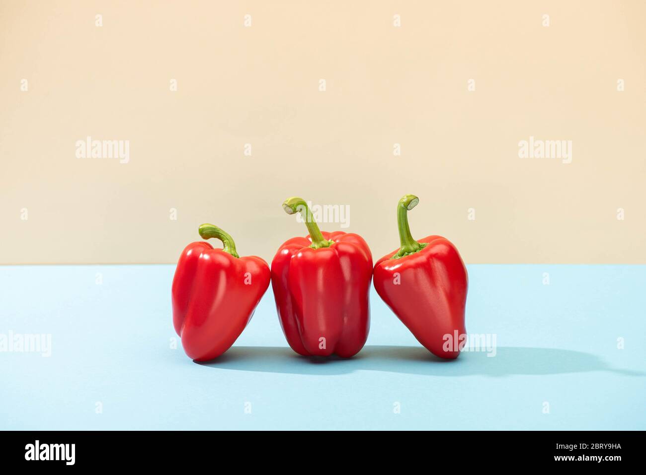 fresh red bell peppers on blue surface isolated on beige Stock Photo ...