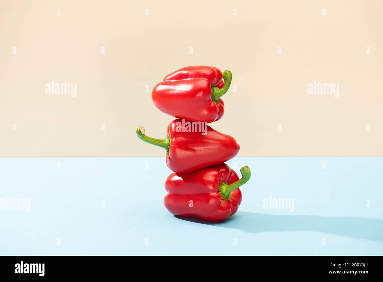 fresh red bell peppers on blue surface isolated on beige Stock Photo ...