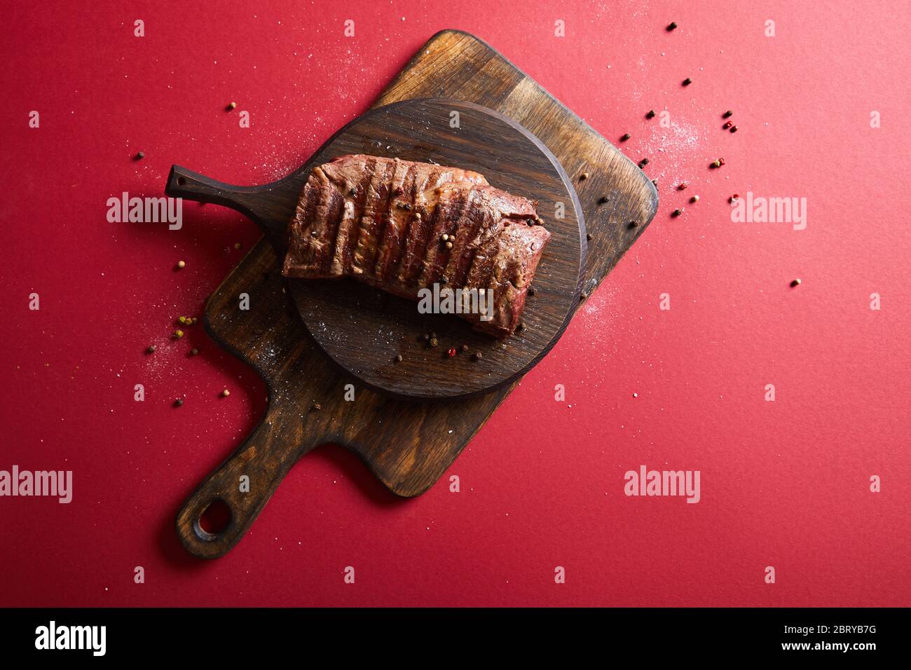 top view of tasty grilled steak served on wooden boards on red ...
