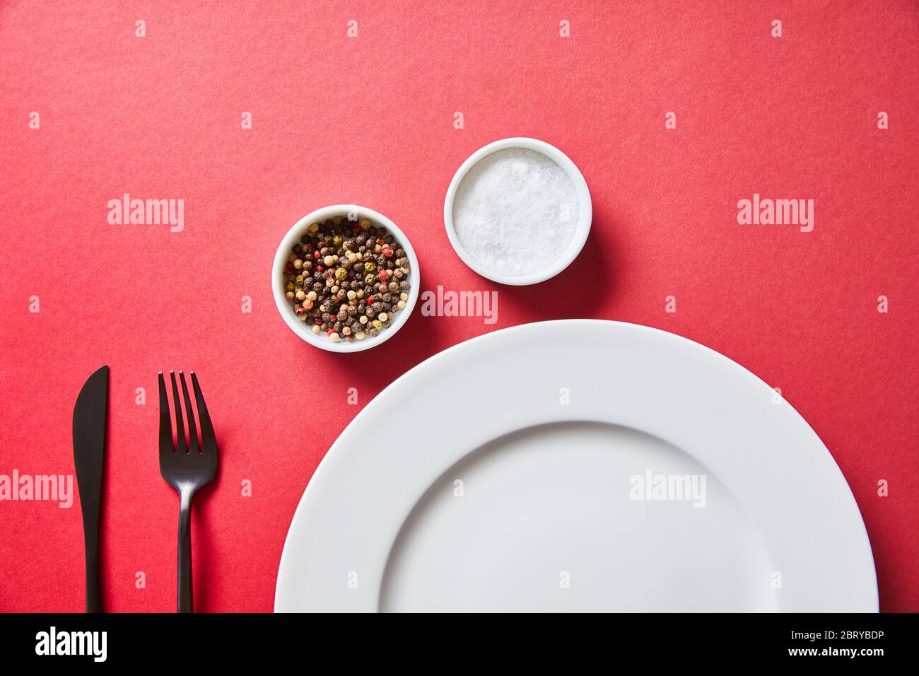 top view of empty round plate with cutlery and salt and pepper in bowls ...