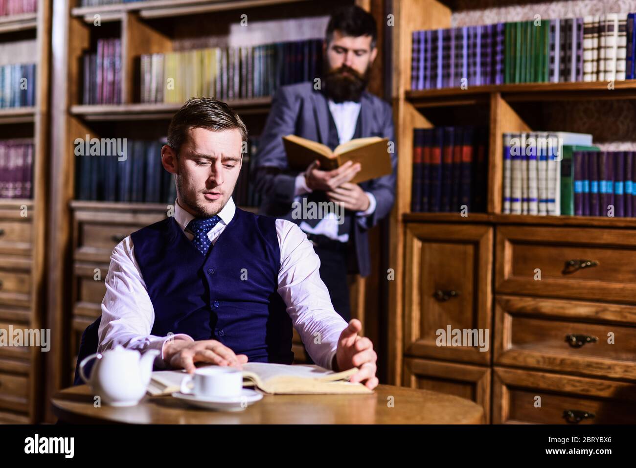 Retro detectives work on investigation and drink tea in antique room ...