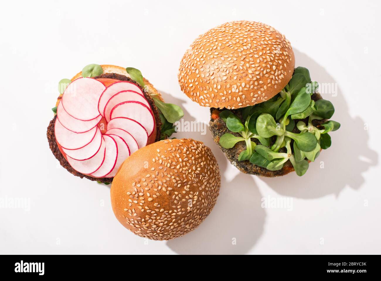 top view of vegan burgers with microgreens, radish on white background ...