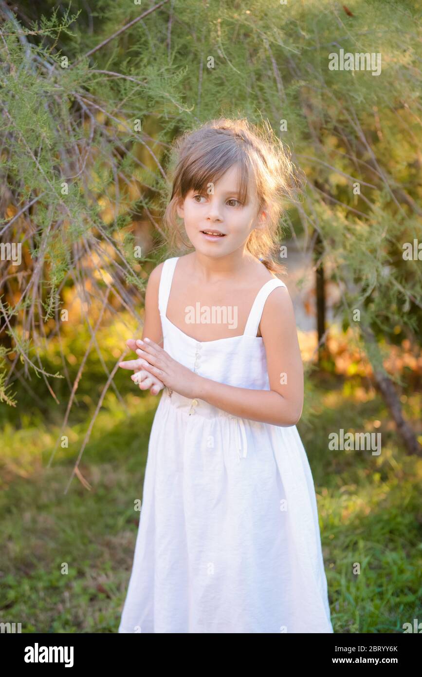 Portrait of girl wearing white summer dress standing in garden Stock ...