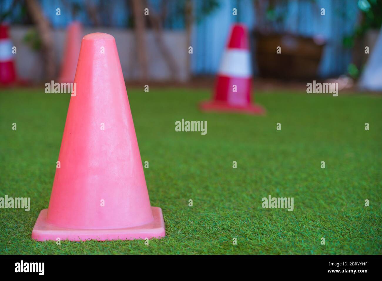 One red plastic small traffic, sport cone for on artificial green grass ...