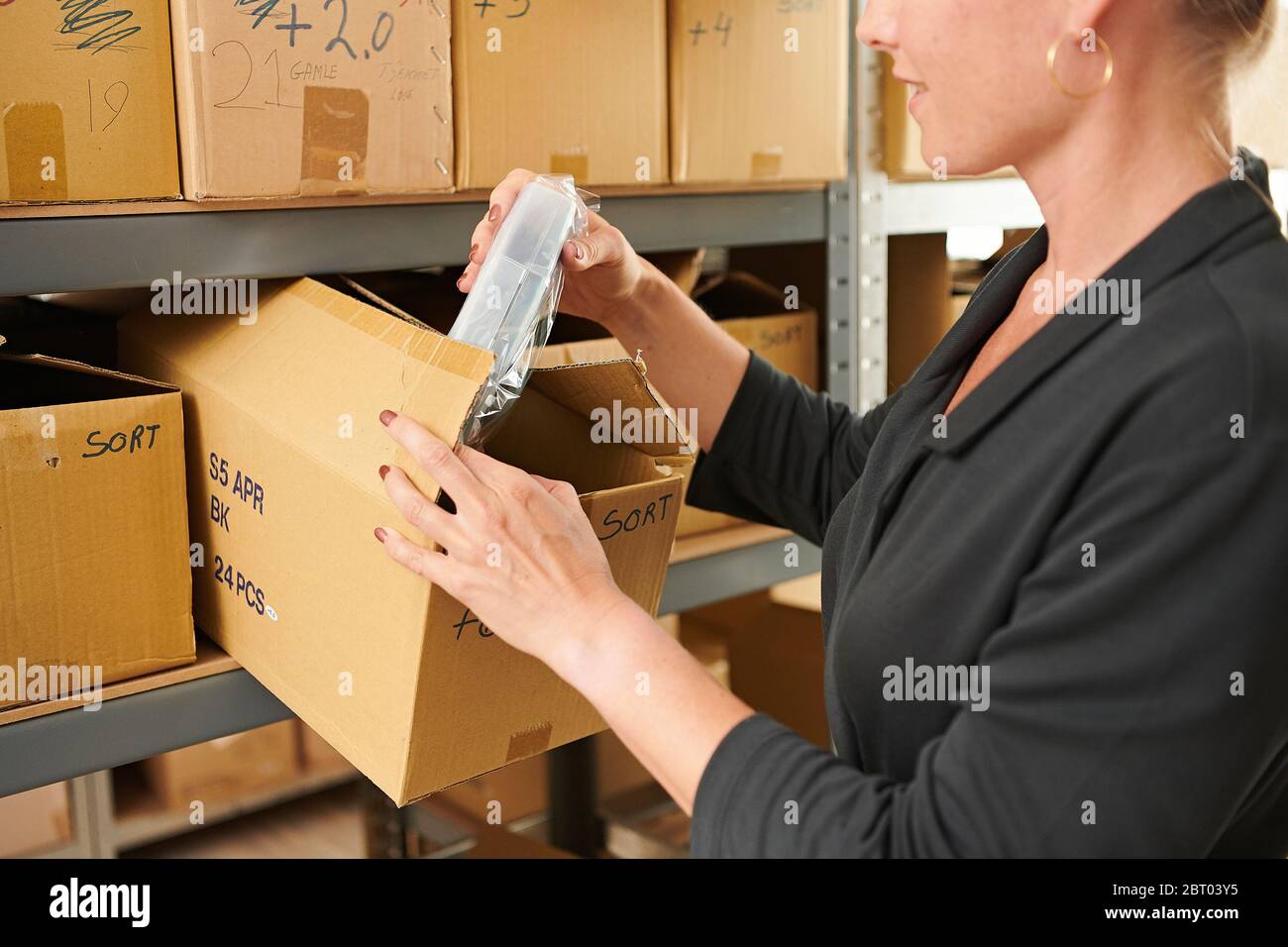 A woman sorting stocks on shelves in a small business Stock Photo - Alamy