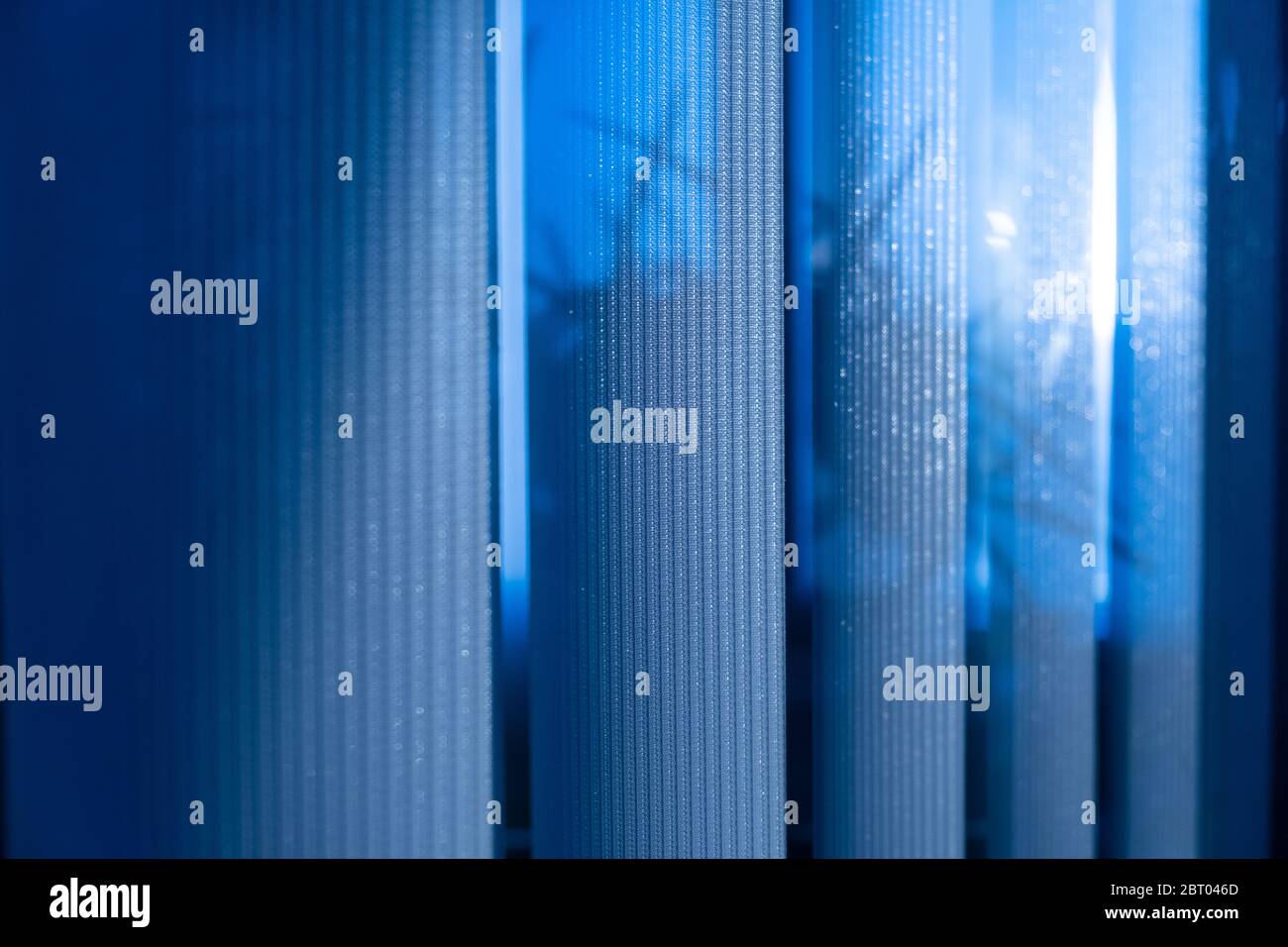 Vertical wide blinds outside the window in the light of the sunset, a ...