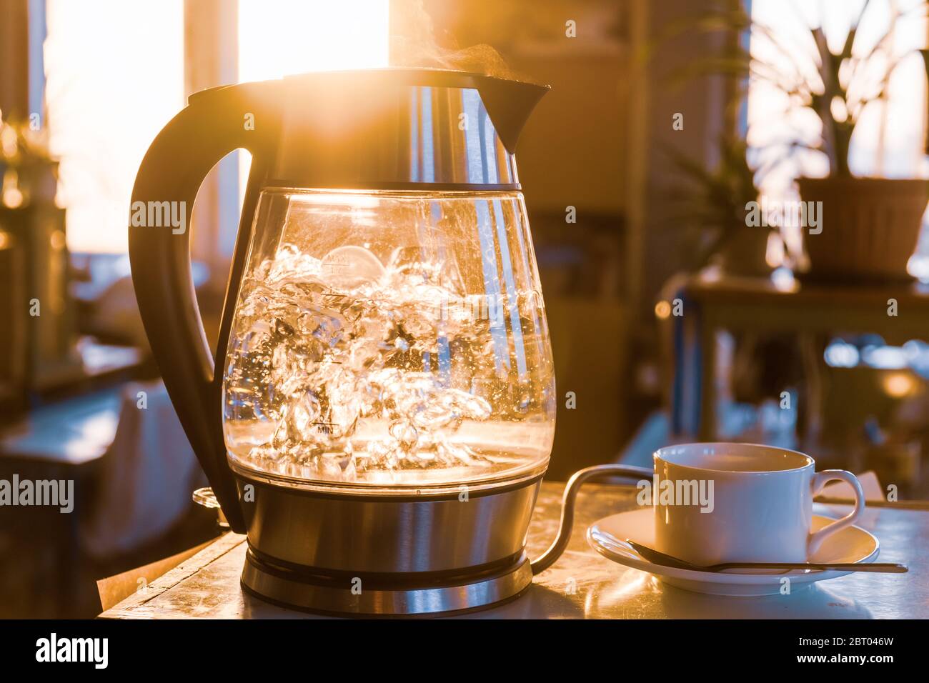 A transparent kettle of water boils against the background of the ...