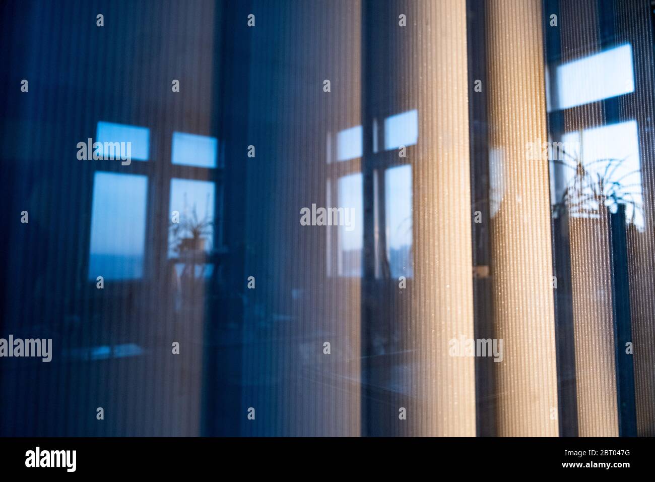 Vertical wide blinds outside the window in the light of the sunset, a ...