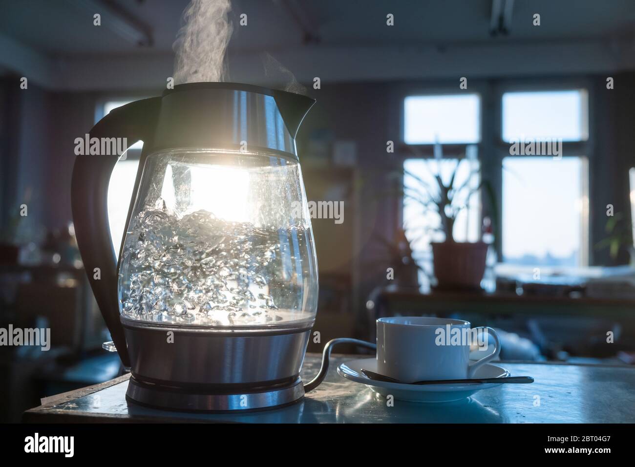 A transparent kettle of water boils against the background of the ...