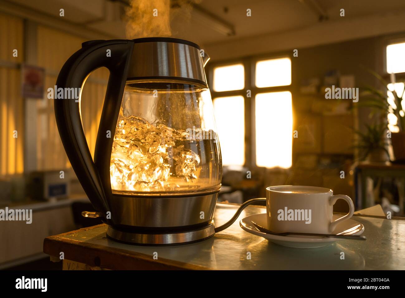 A transparent kettle of water boils against the background of the ...