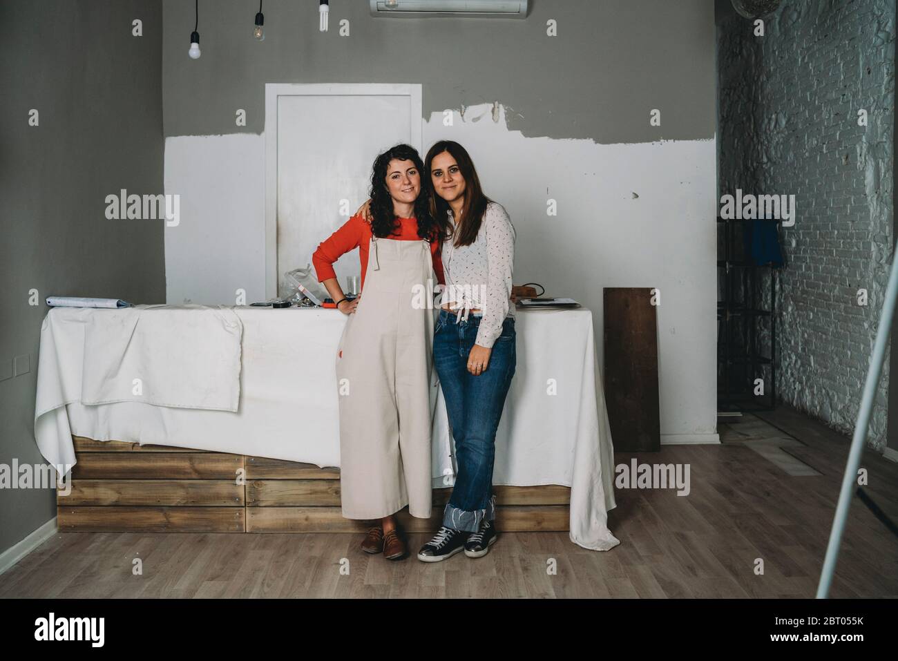 Two mid adult women leaning against table while painting in their new ...