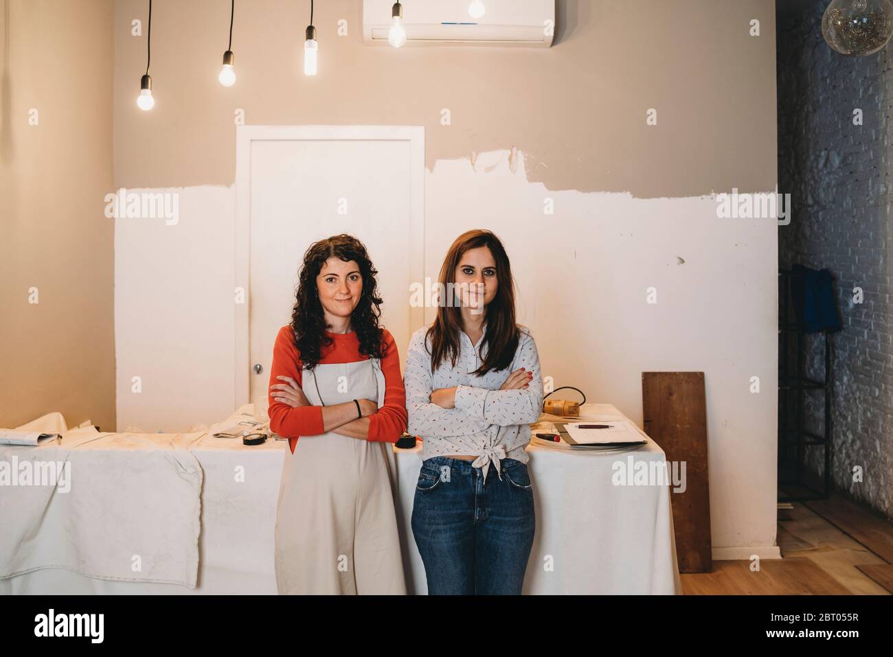 Two mid adult women leaning against table while painting in their new ...