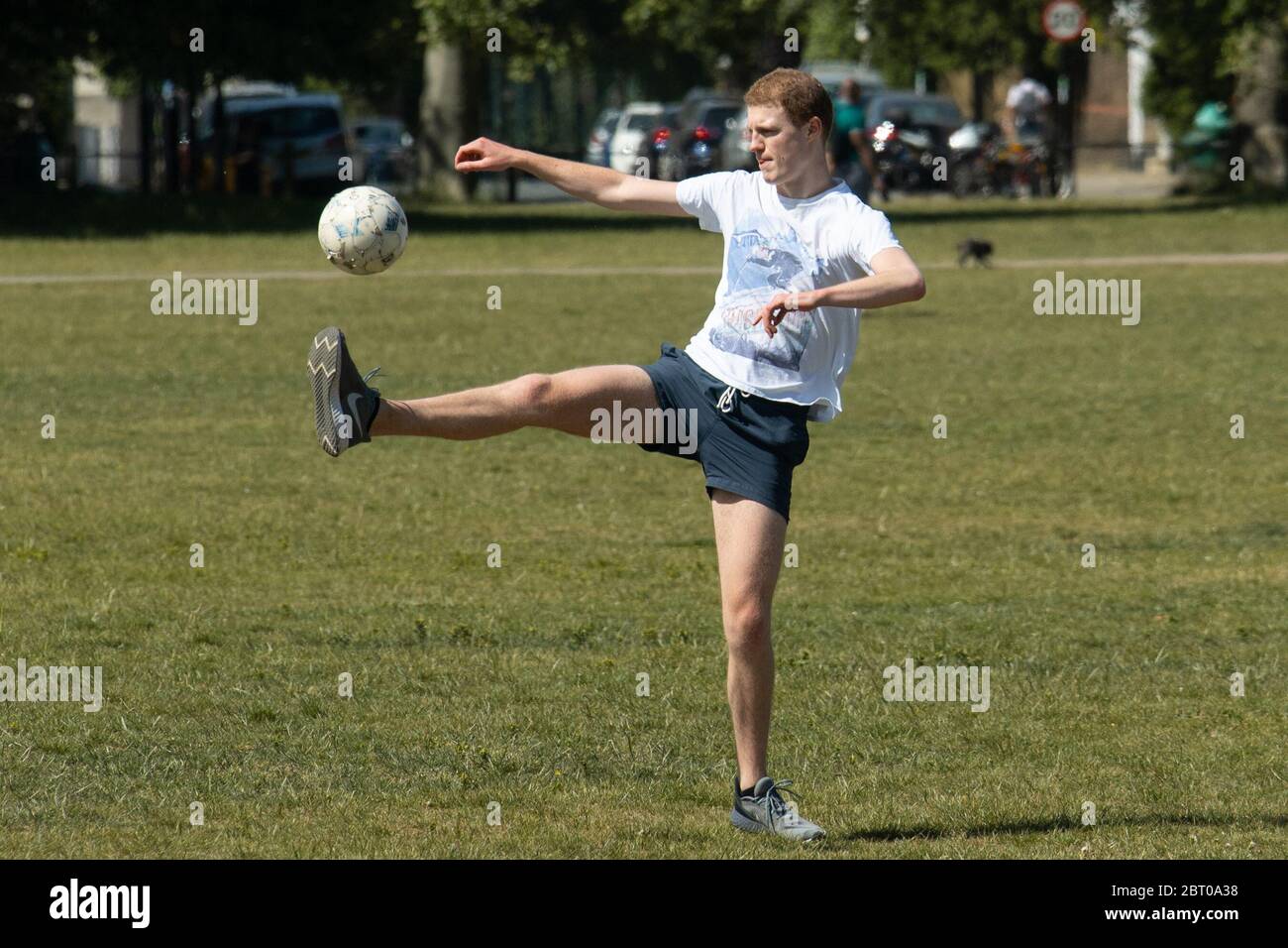 A man plays football in the hot weather on Clapham Common, London Stock ...