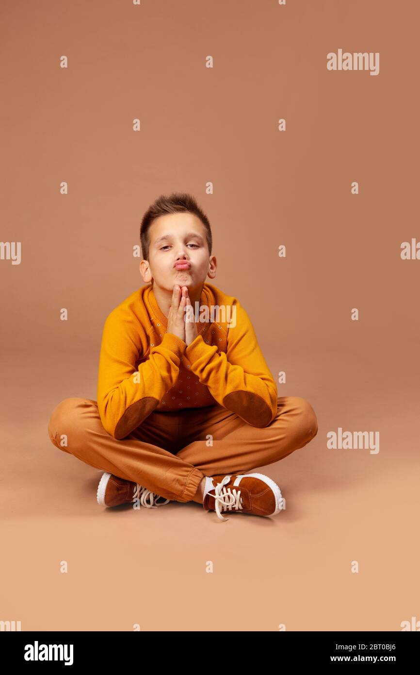 the boy joined his palms and protruded his lips, sitting in a Turkish ...