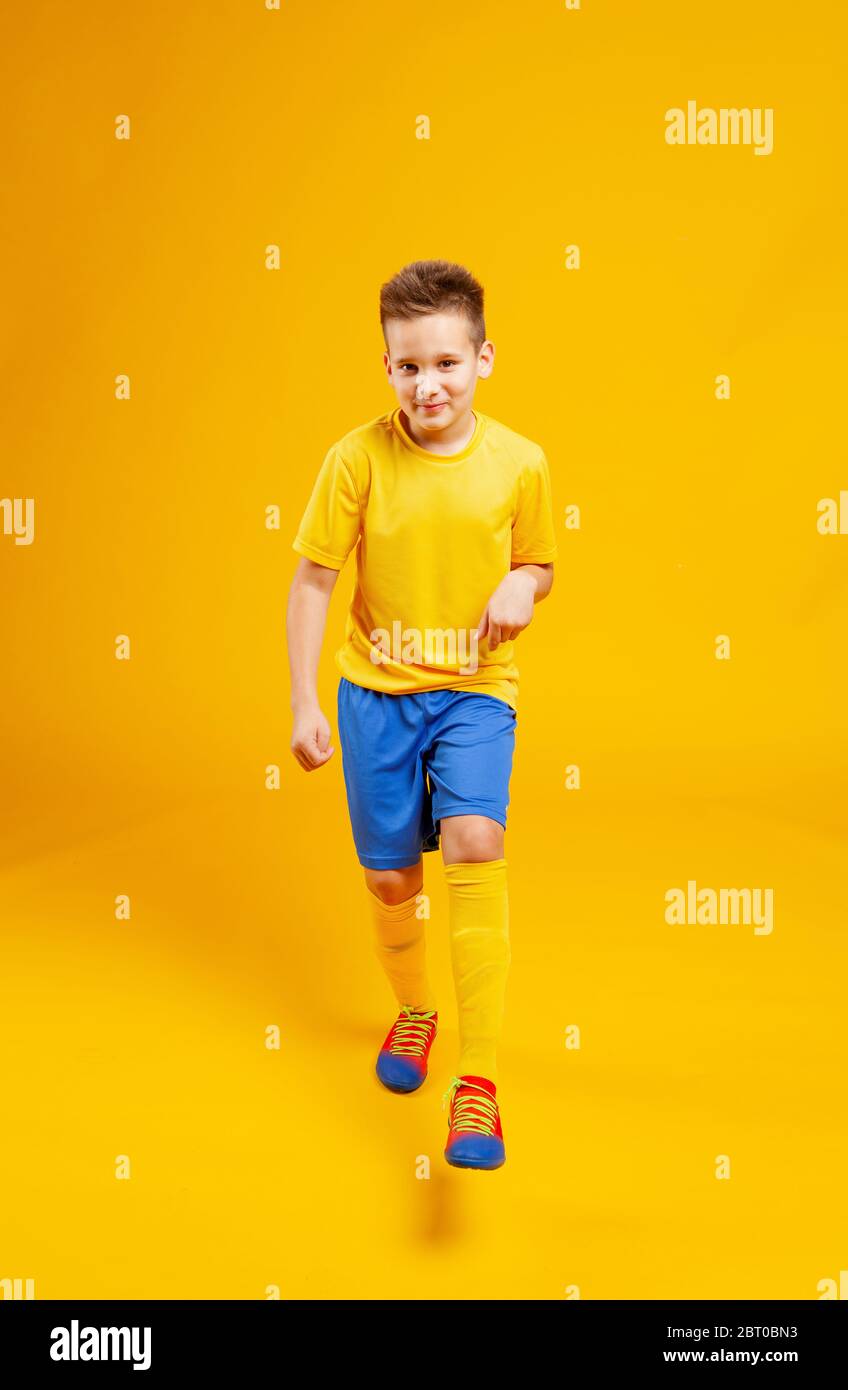 running boy in soccer uniform on a yellow background Stock Photo - Alamy