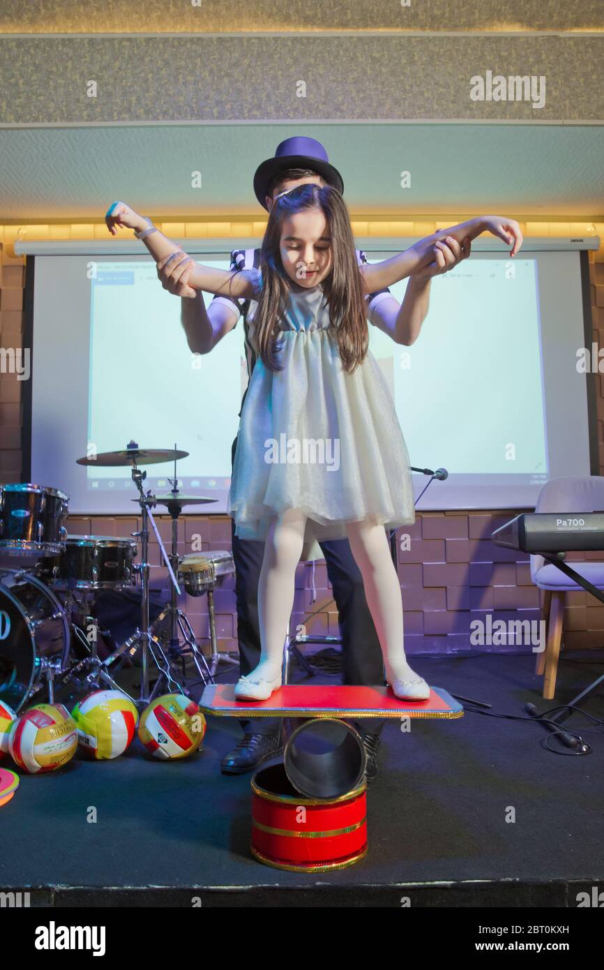 Kids standing on top of cylinders and juggling glass bottles, one ...