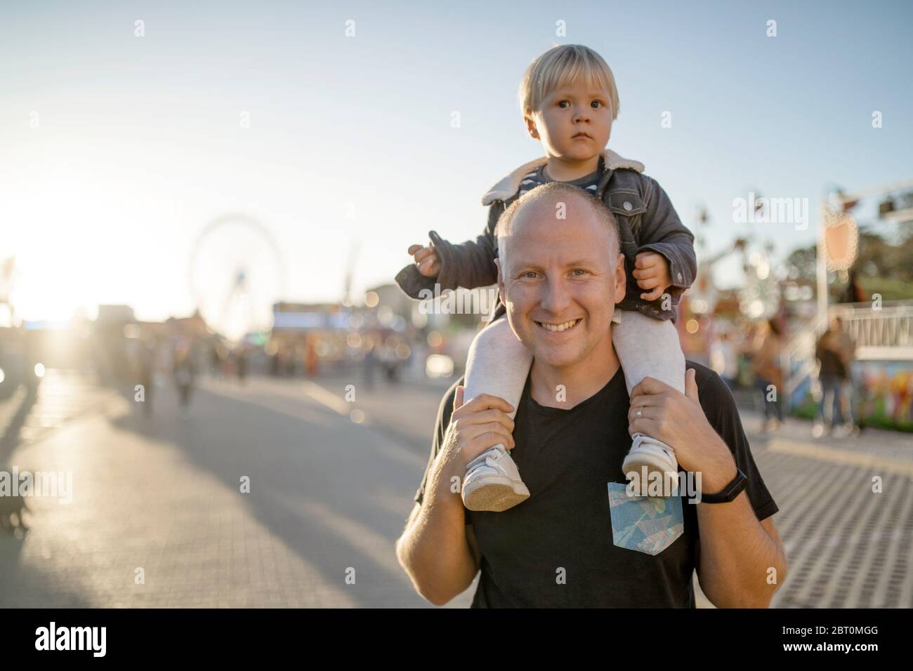Happy father with his little piggybacked son in an amusement park Stock ...