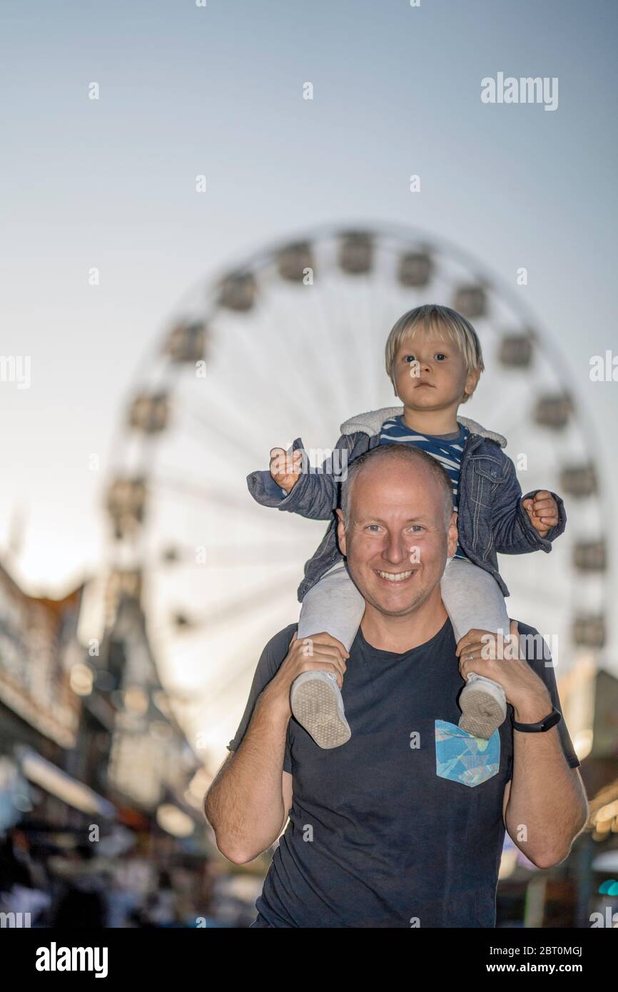 Happy father with his little piggybacked son in an amusement park Stock ...