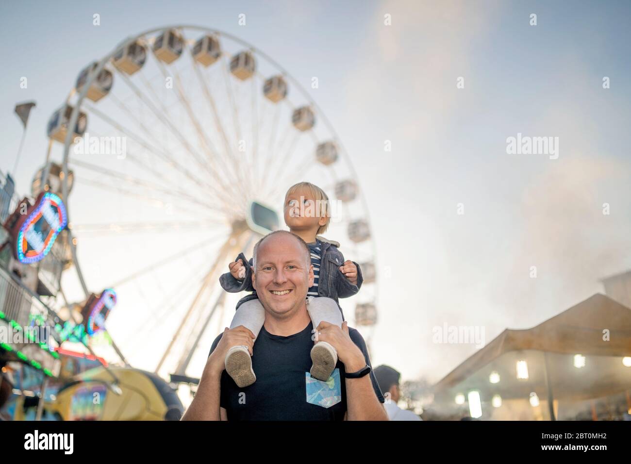 Happy father with his little piggybacked son in an amusement park Stock ...